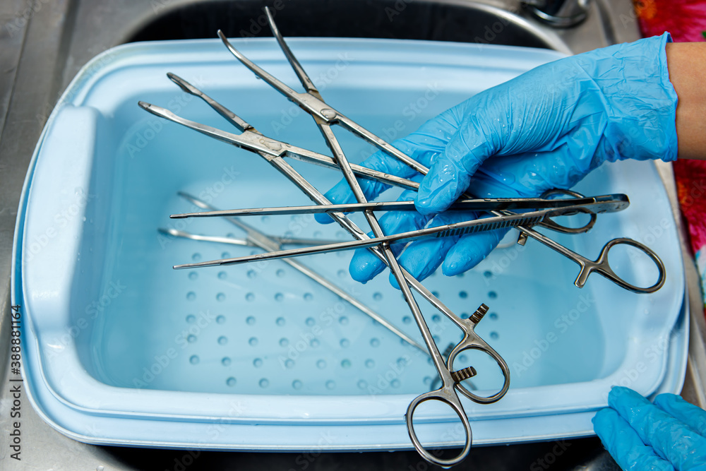 A medical worker rinses surgical instruments in a tray of water ...