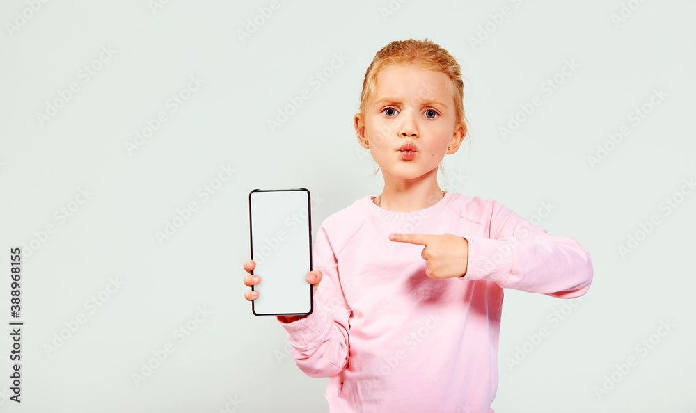 Smiling little pretty girl in pink showing white blank screen of mobile ...