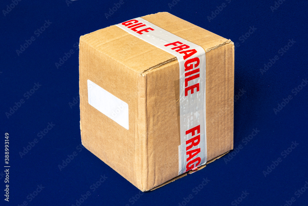 A cardboard shipping box, securely wrapped with tape indicating the ...