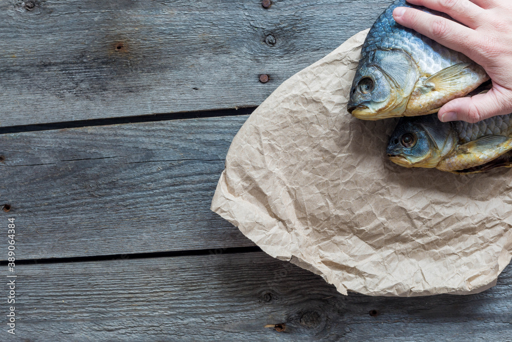 Hand holds Dried Volga bream vobla in a crumpled kraft paper roll Stock ...