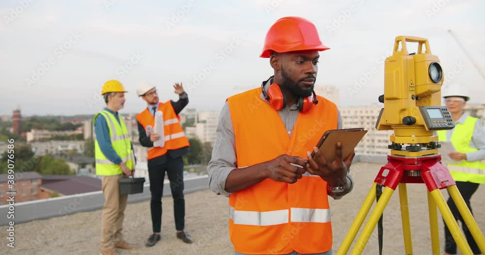 African American man topographer in casque measuring angle with total ...