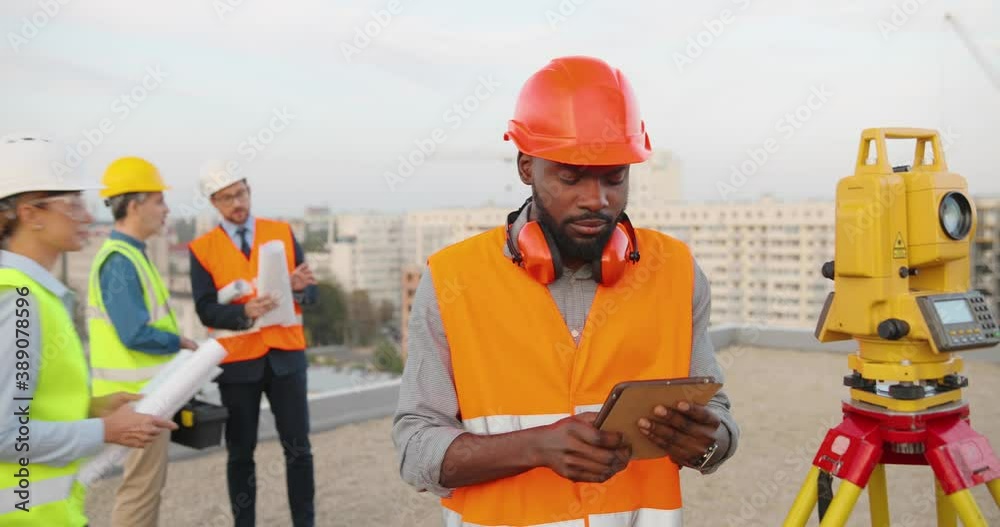 African American man topographer in casque measuring angle with total ...