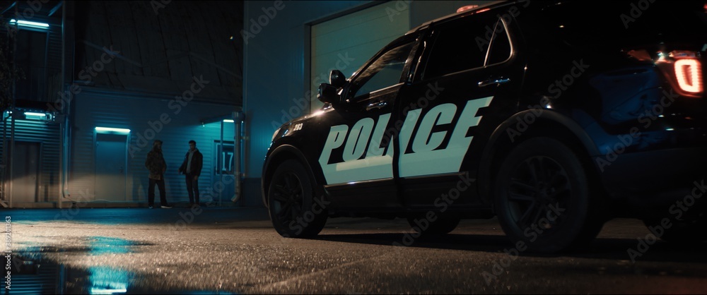 WIDE Police car turns on flashing lights while approaching two multi ...