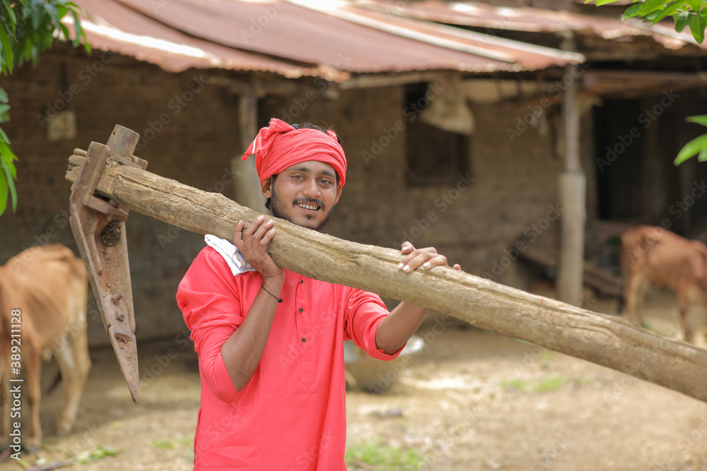 Indian farmer in traditional wear and holding farm equipment in hand ...