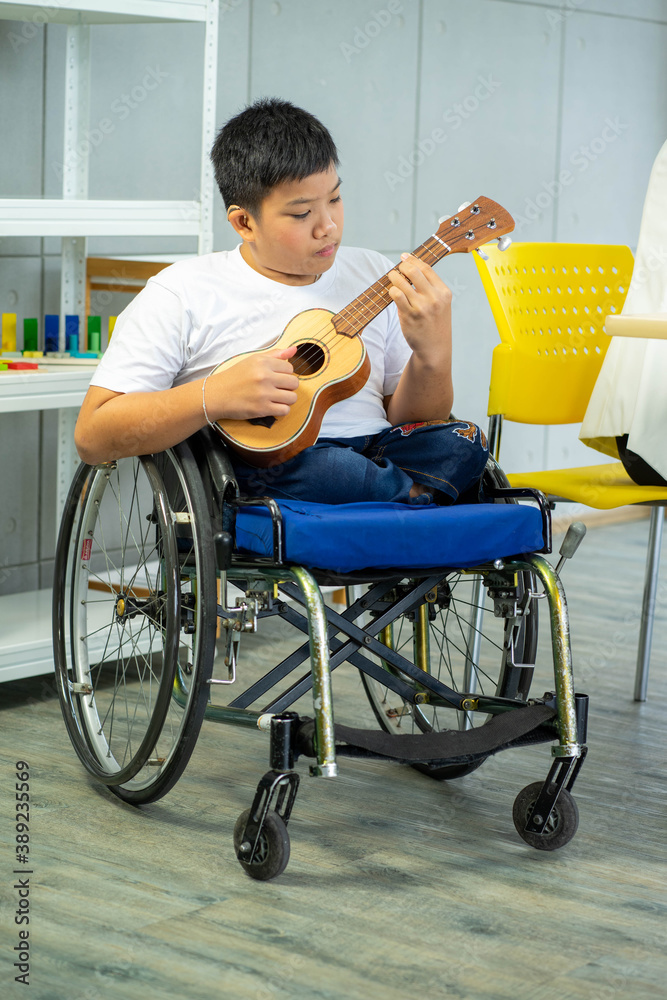 disability kid playing music with guitar on wheelchair with Autism ...
