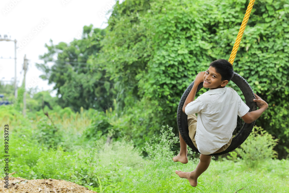 Cute indian child playing on swing made by tyre and rope on tree at ...