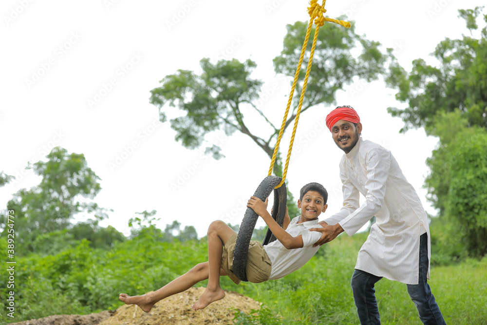 Cute indian child playing with his father on swing made by tyre and ...
