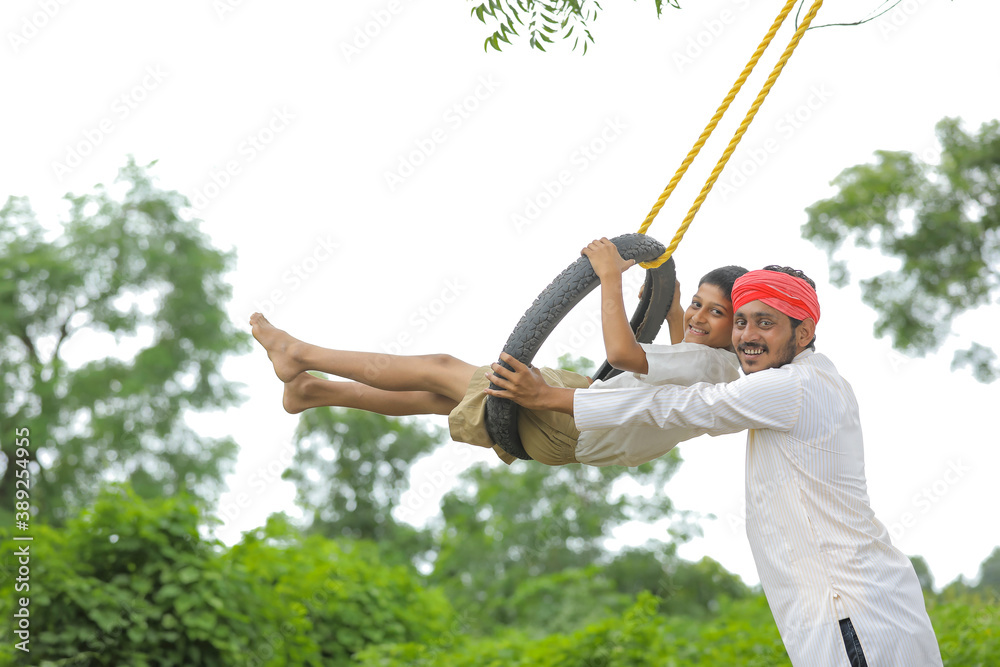 Cute indian child playing with his father on swing made by tyre and ...