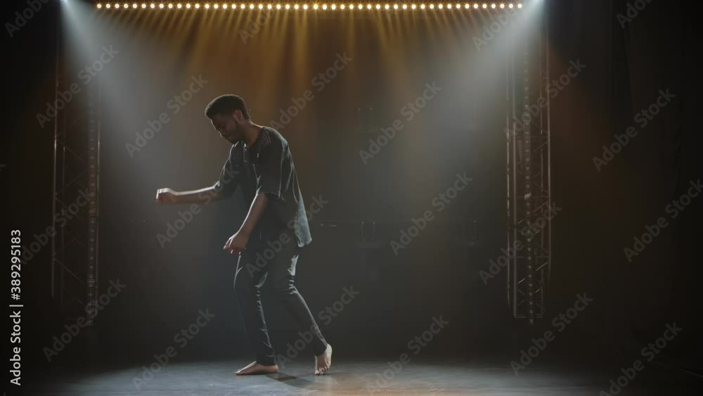 Attractive African American man dancing folk ethnic dance in a dark ...