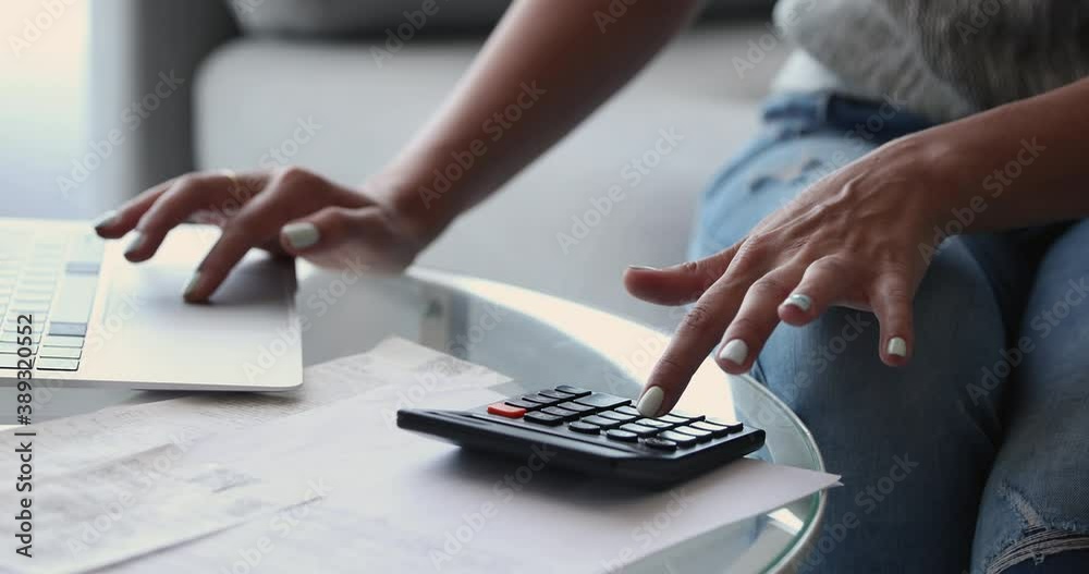 Close up young woman using calculator, and laptop e-banking application ...