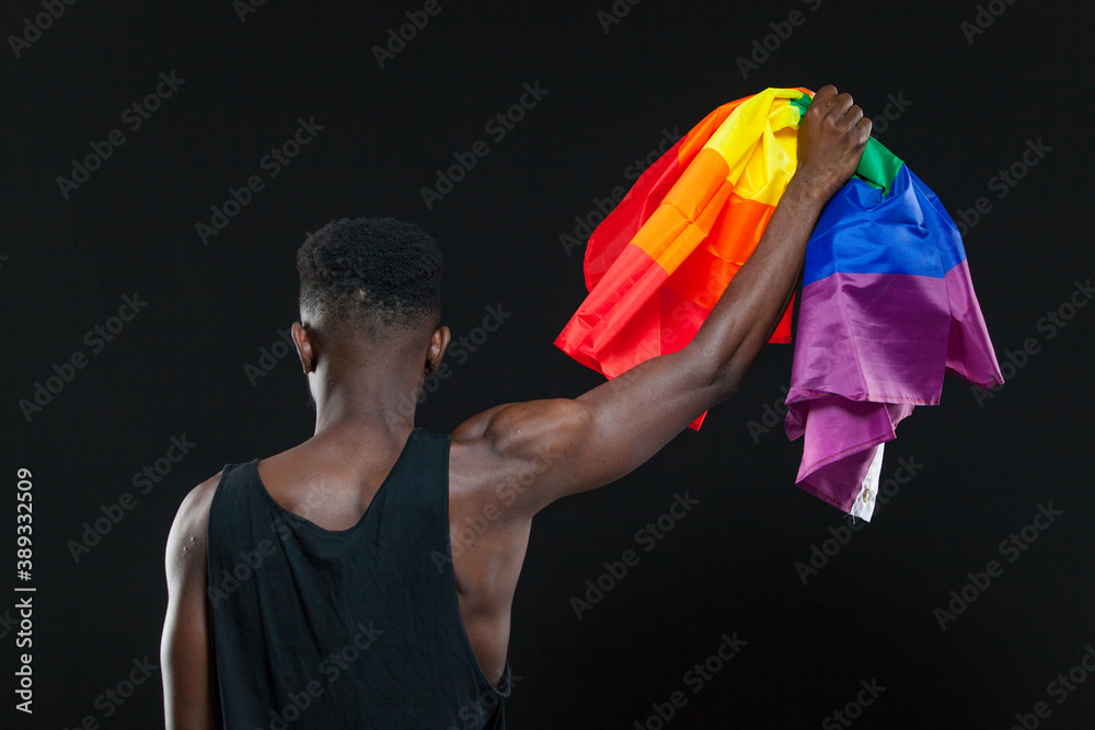 Back view of young african american man holding a rainbow flag in a ...