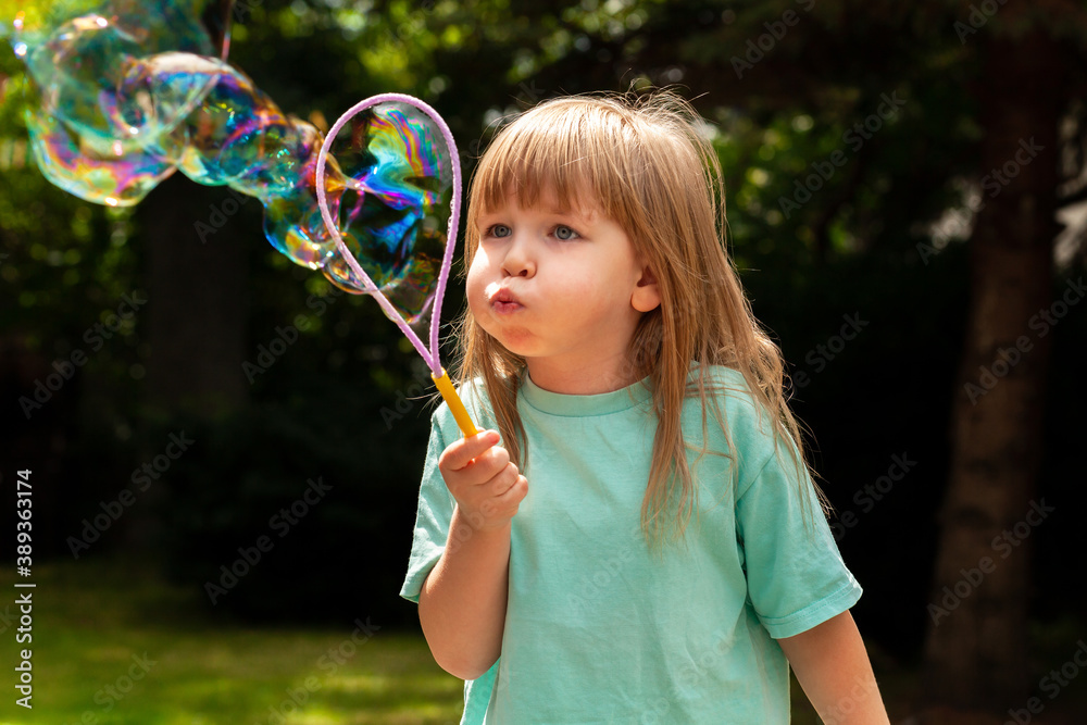 Little child, girl blowing huge bubbles alone, portrait outdoors. Young ...