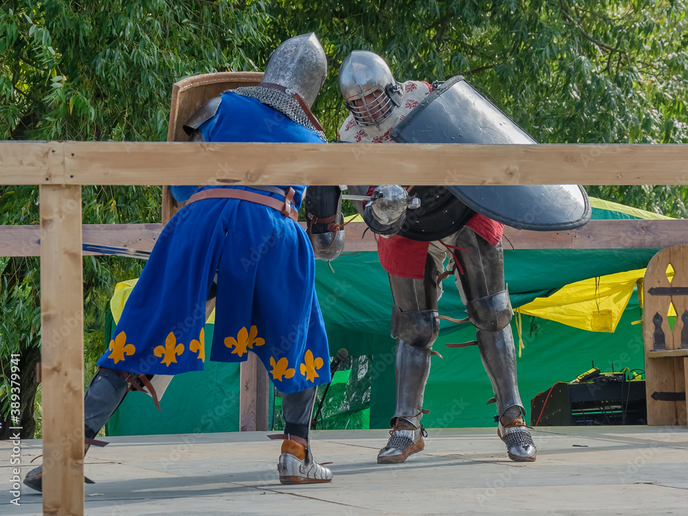 Two foot warriors in heavy medieval armor fight in the arena. Armed ...