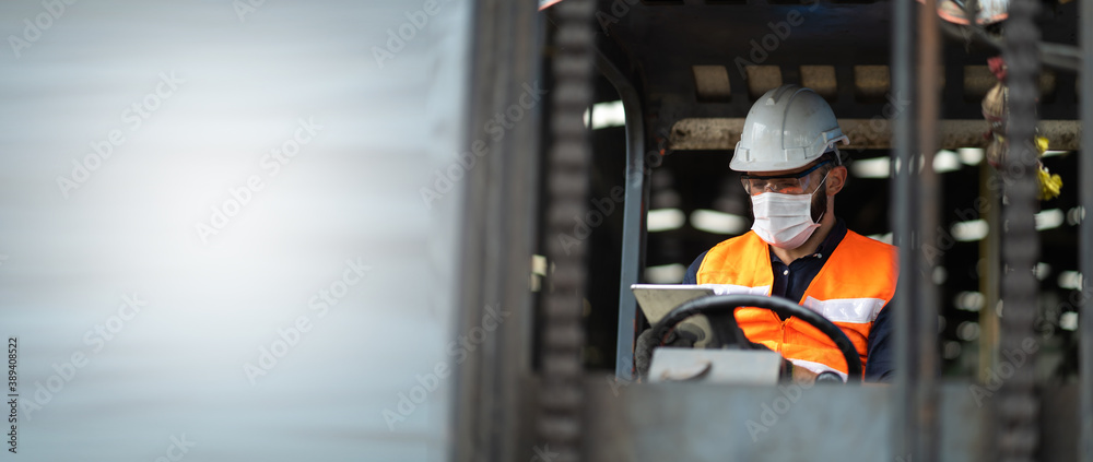 Young male staff driving forklift in warehouse. Worker man wearing face ...