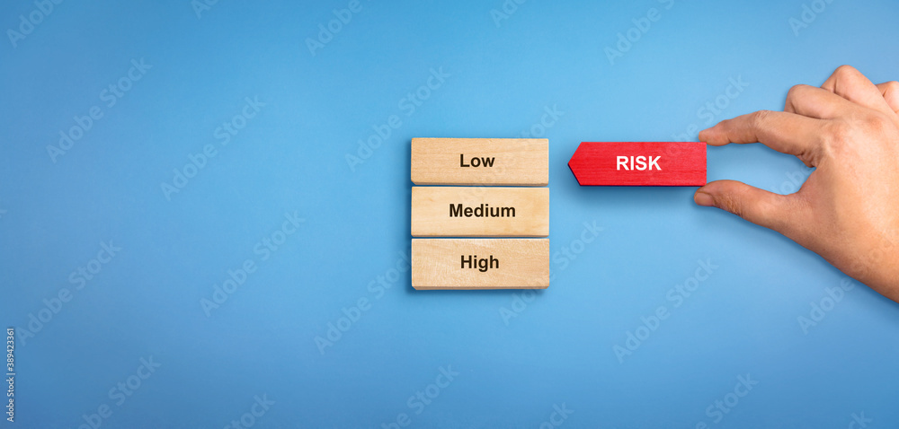 Risk concept with text high, medium and low. Hand holding wooden block ...
