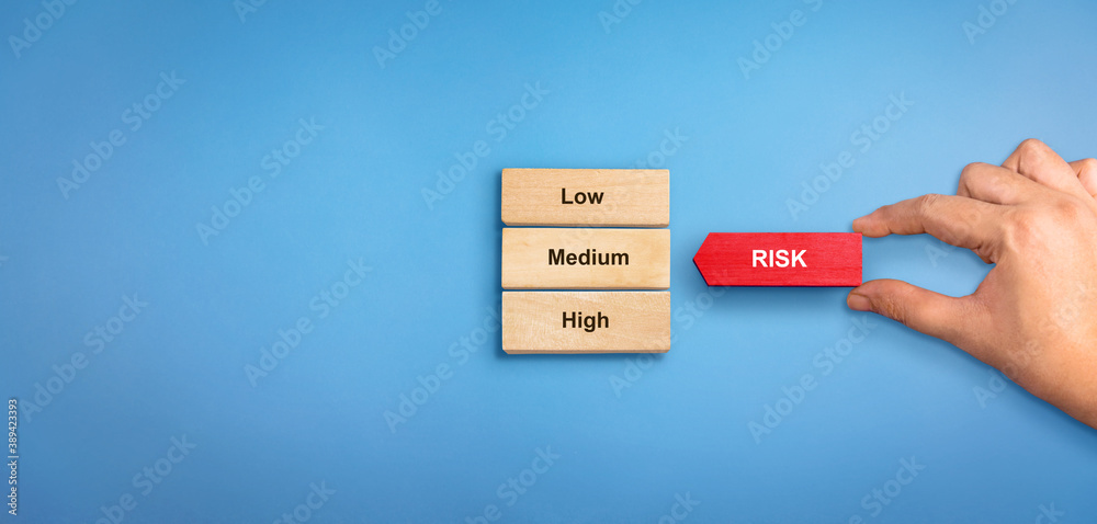 Risk concept with text high, medium and low. Hand holding wooden block ...
