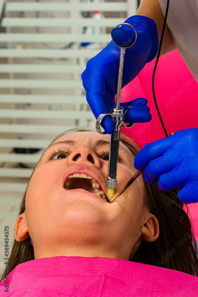 The dentist with the help of a carpule syringe injects anesthesia into ...