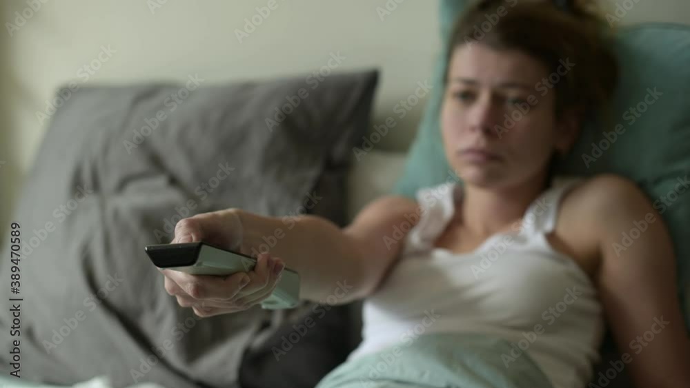 The TV control panel is in the hands of a tired, sick young woman who ...