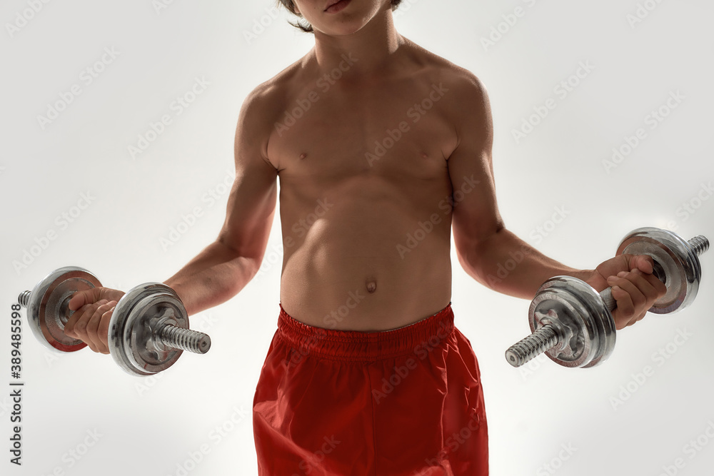 Cropped shot of little sportive boy child with muscular body lifting ...