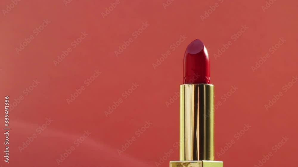 Chic red lipstick in golden tube and shining light flares, luxury make ...