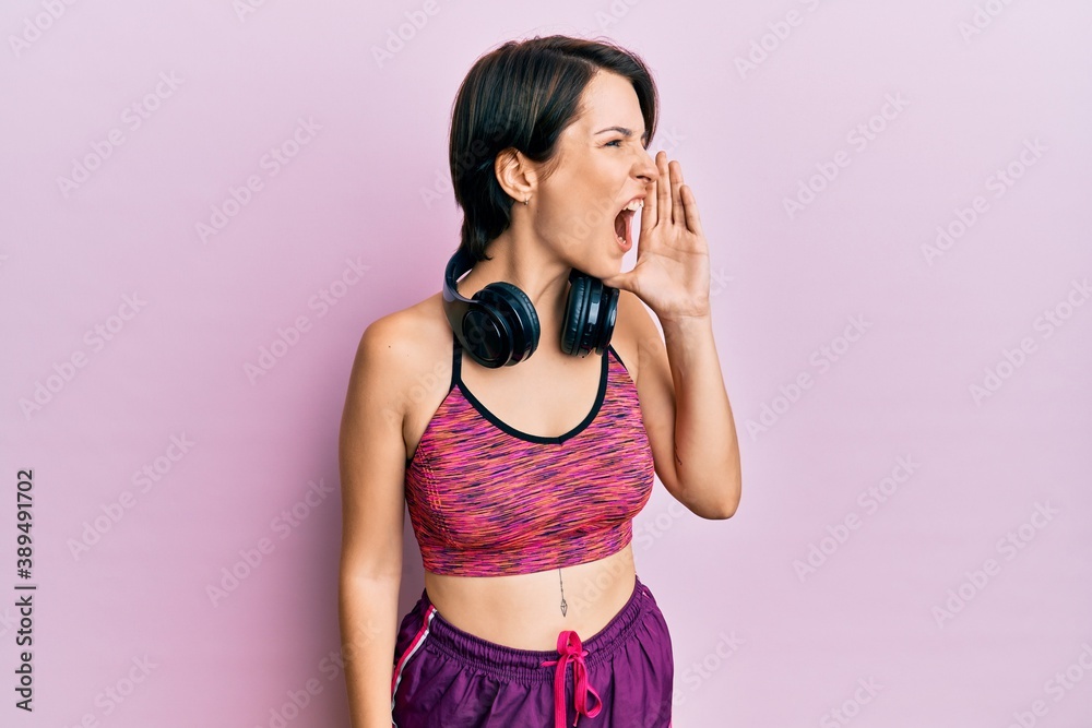 Young brunette woman with short hair wearing sportswear and headphones ...