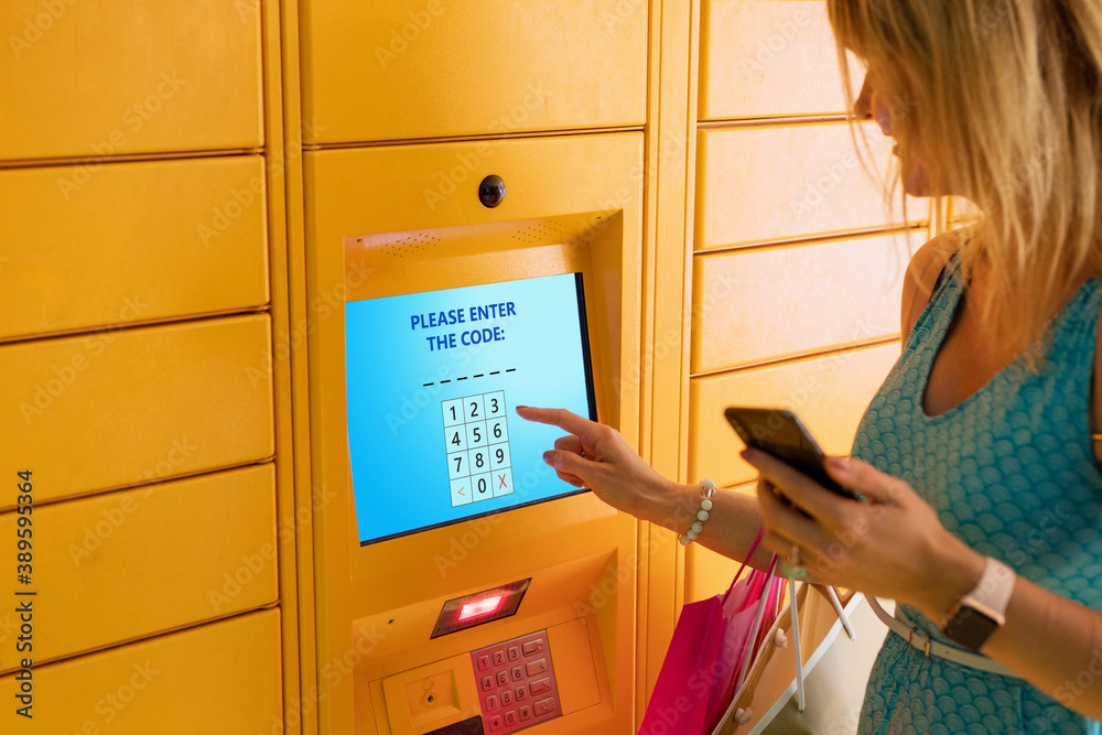 Woman entering code to receive parcel in post locker Stock Photo ...