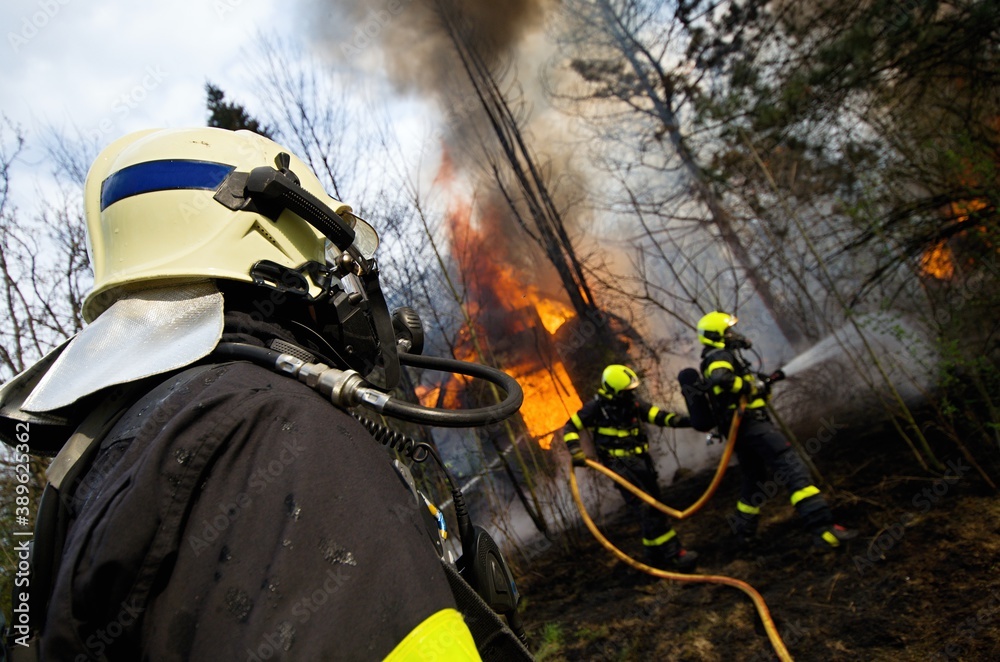 Firefighters use water to extinguish a huge fire in several wooden ...