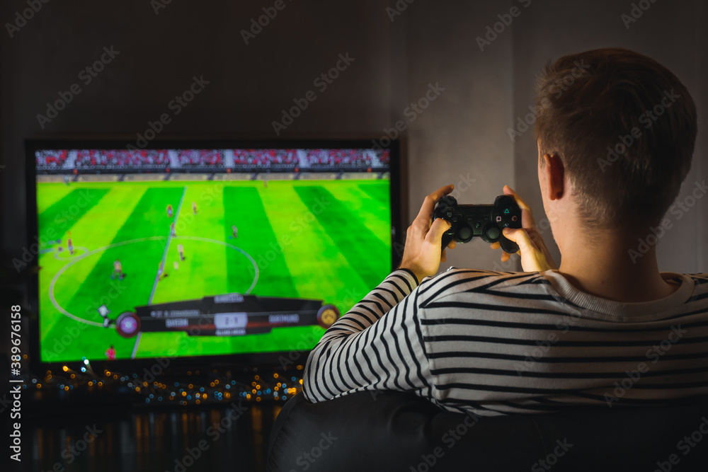Young hipster man playing video game football soccer on console. gamer ...