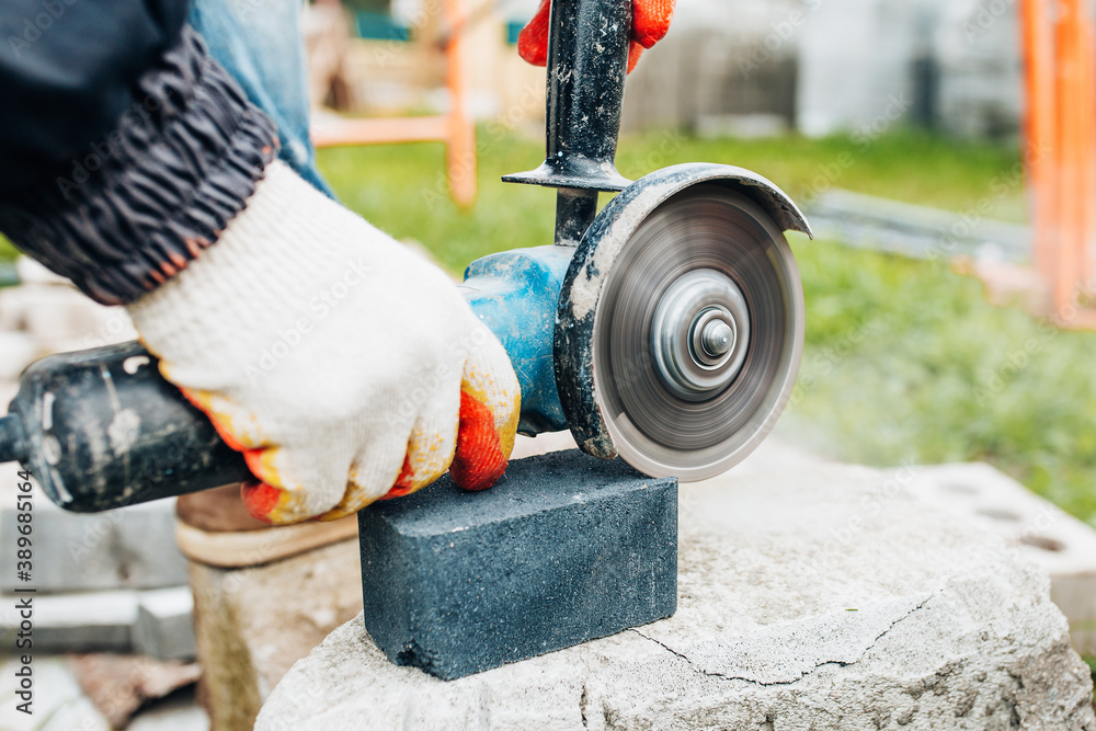 A grinder in the hands of a tiler - a diamond disc with dust cuts stone ...