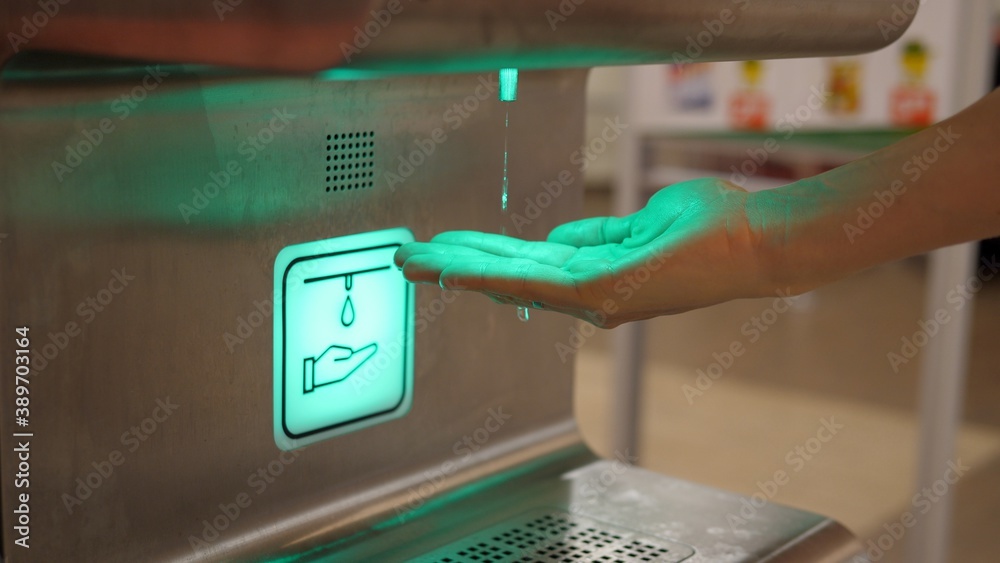 Side view of person using hands free sanitizer dispenser device in ...