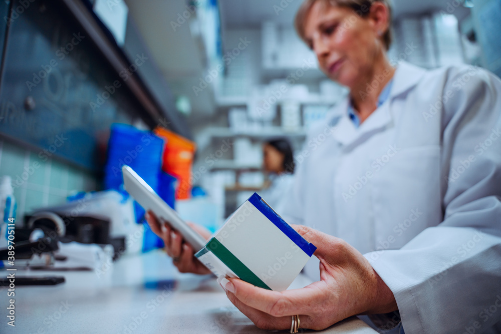 Elderly pharmacist reading label of prescription medication box ...