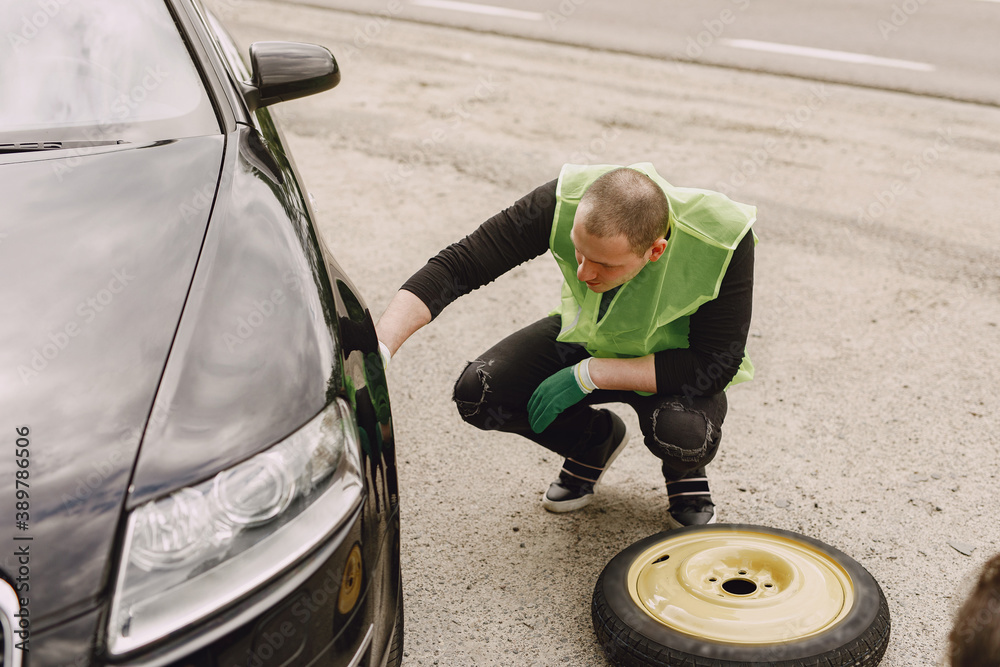 Worker changes a broken wheel of a car. The driver should replace the ...