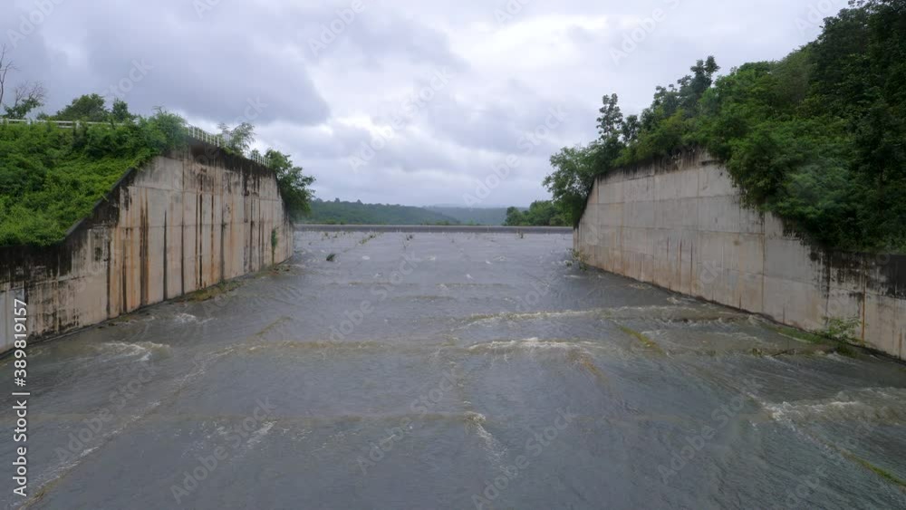 Plenty of water falling from the concrete reservoir dam spillway ...