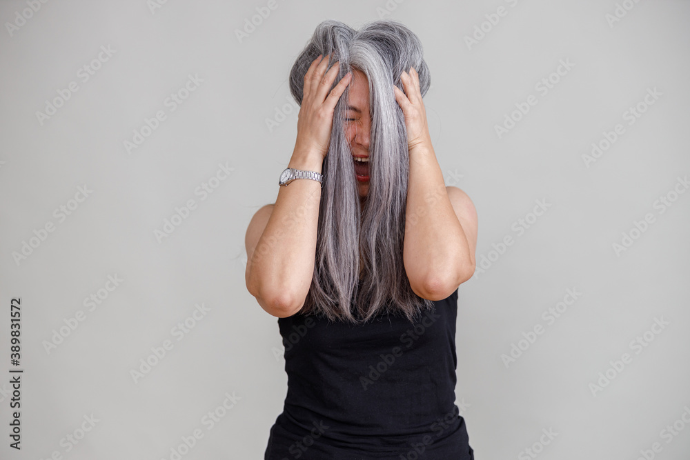 Emotional portraits of a paled long hair asian matured woman on grey ...