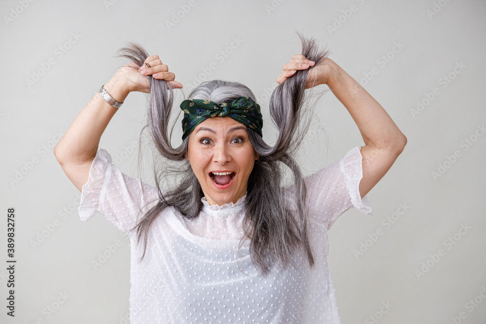 Emotional portraits of a paled long hair asian matured woman on grey ...