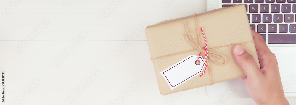 Hand holding gift box and tag having laptop computer on wooden table ...