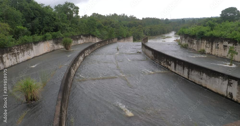 Plenty of water falling from the concrete reservoir dam spillway ...