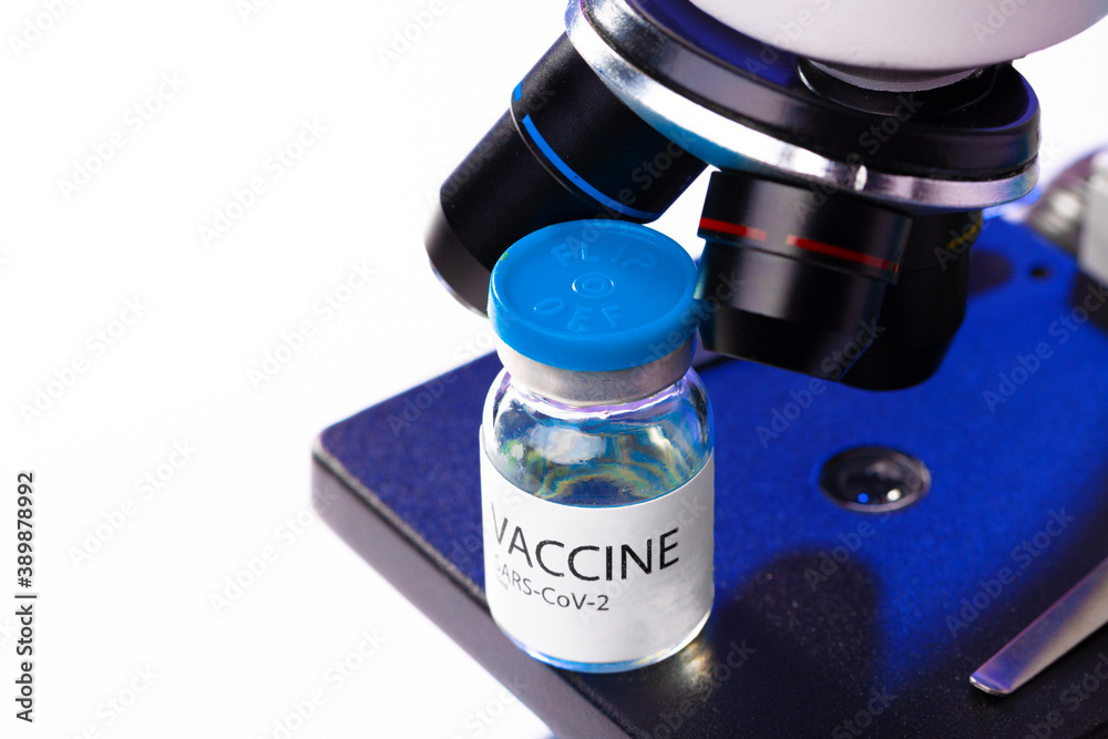 Vial of Covid-19 vaccine next to a microscope Stock Photo | Adobe Stock