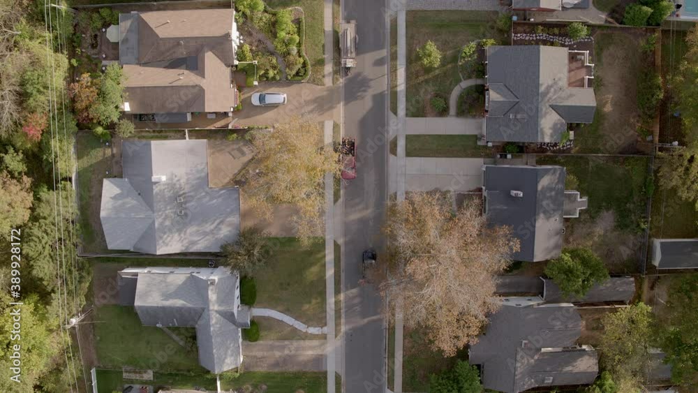 Overhead view of suburban neighborhood in Autumn as a car drives down ...