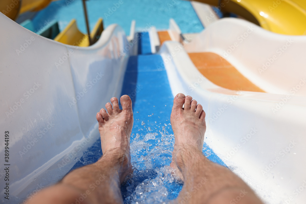 Male feet with splashing water on slide in water park. Entertainment in ...