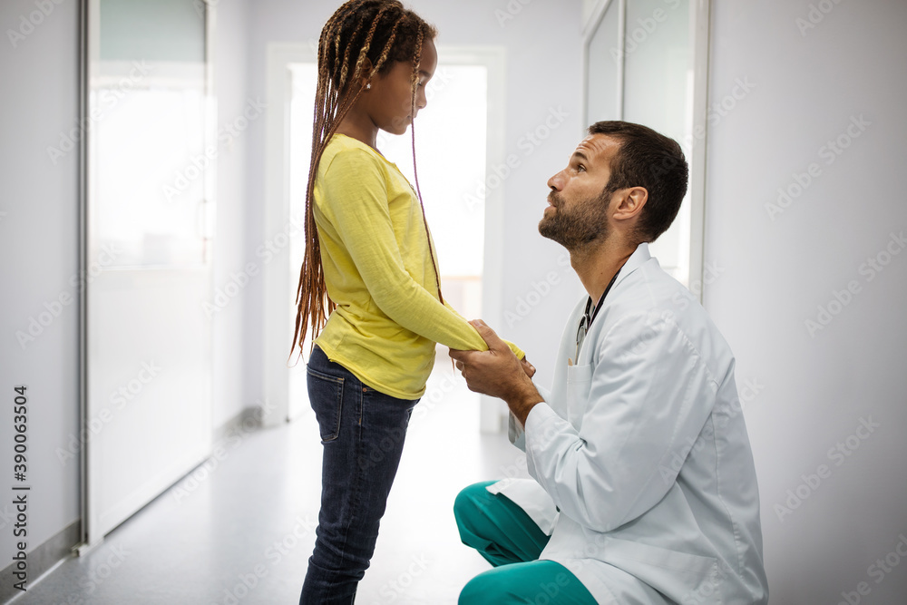 Doctor having conversation with sad little girl at the hospital. Doctor ...