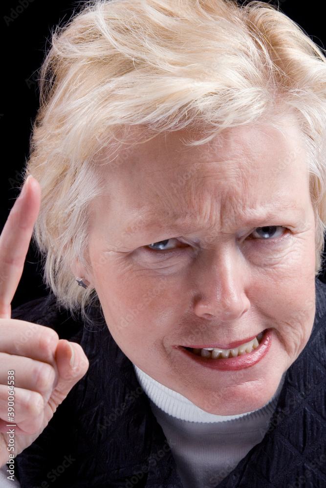 Studio photo of older woman with an angry look making a warning finger ...