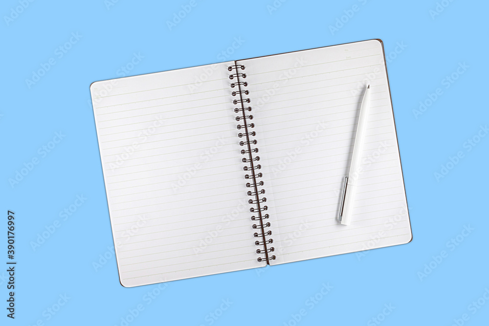 An open spiral notebook with a white ballpoint pen lying on a piece of ...