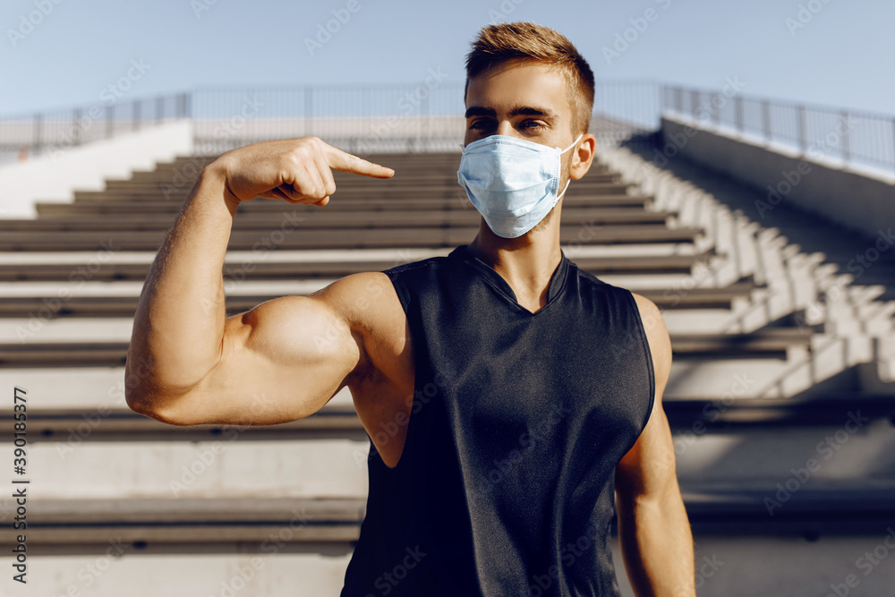 Sporty young muscular man wearing a medical protective mask on his face ...