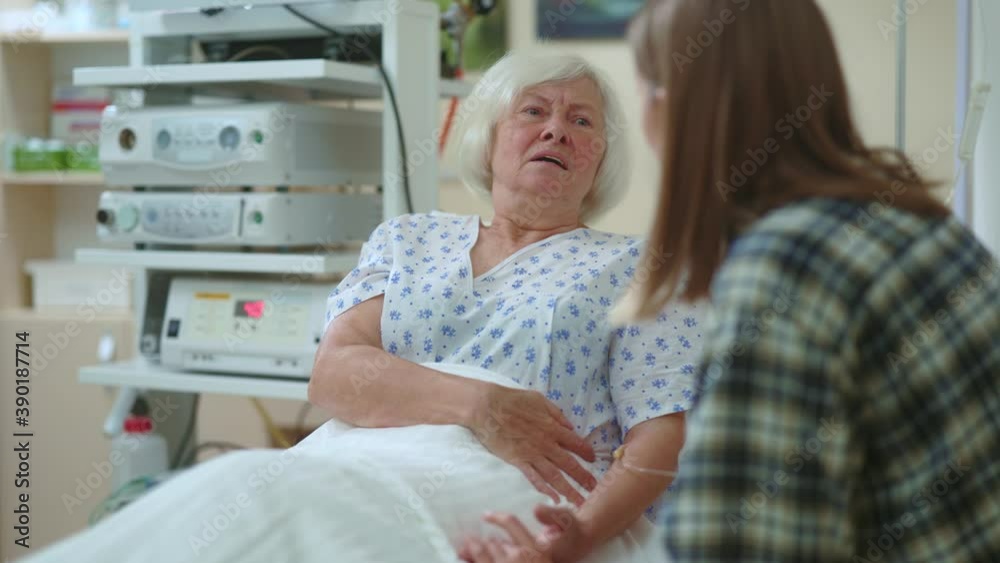 Senior poor old woman suffering gut disease sitting in hospital room ...