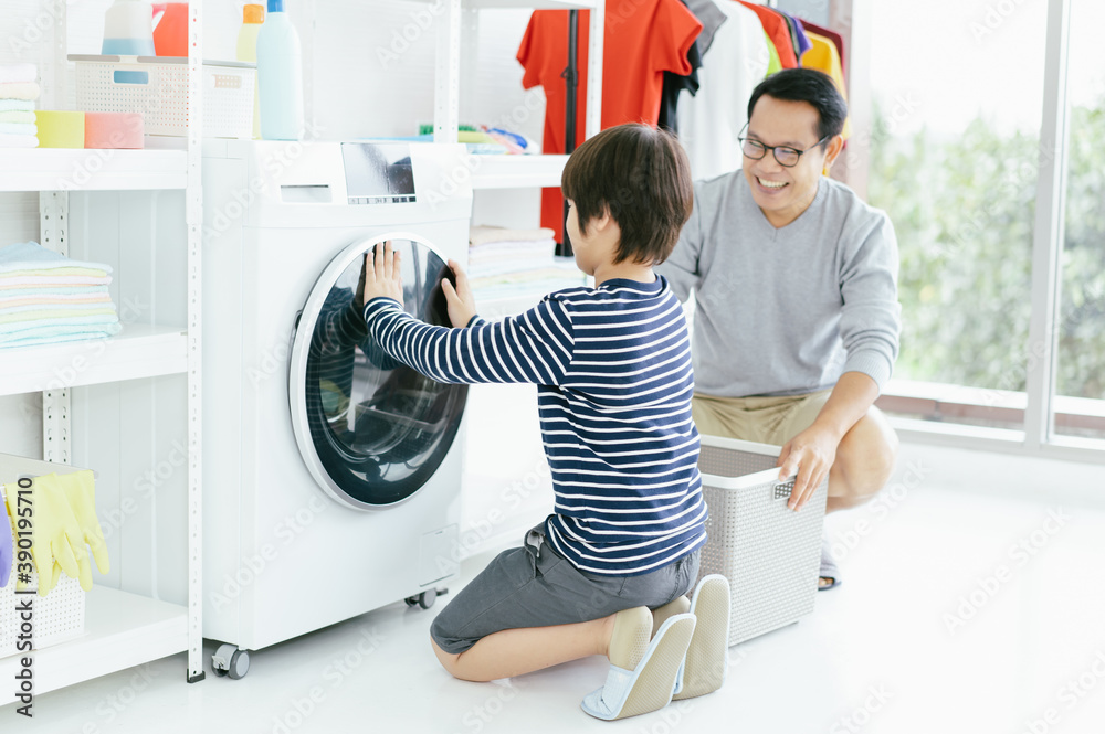 Happy smiling Asian family father and son in the laundry load a washing ...
