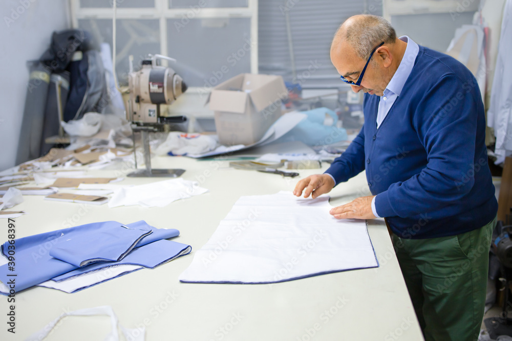 Old tailor prepares paper models in his workshop. Concept of manual ...
