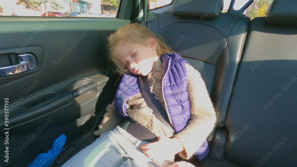 The little girl fell asleep in the back seat of the car. Traveling with ...