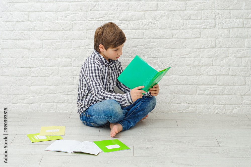 Child boy is reading a book while sitting on the floor with lamps and ...