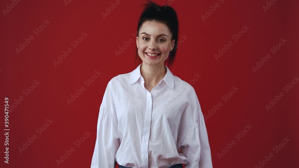 Beautiful young woman in white shirt posing in studio on red background ...